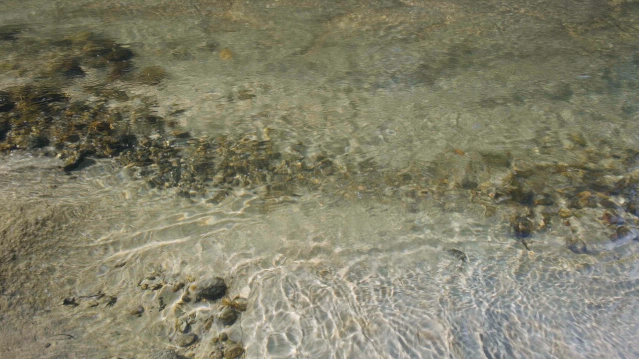Crystal clear water flowing over the sand - Free Stock Video
