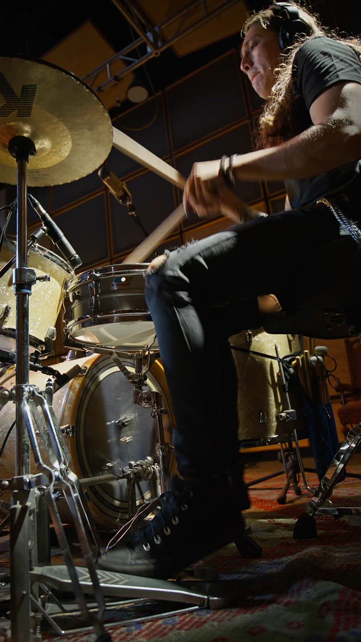 Skilled drummer wearing headphones moves his feet fast while jaming on ...