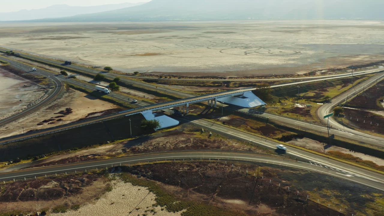 Flying over a highway overpass with a dry lake and mountains in the ...