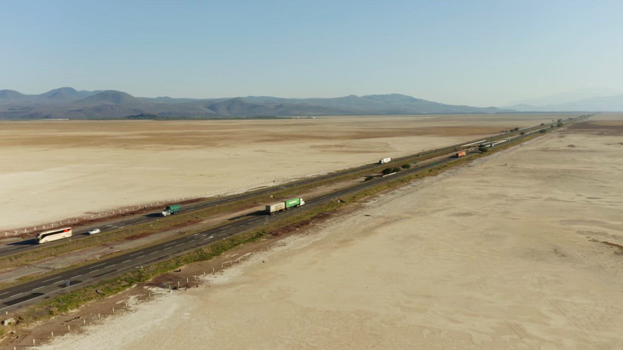 A vast concrete road with vehicles moving through its lanes crosses the ...