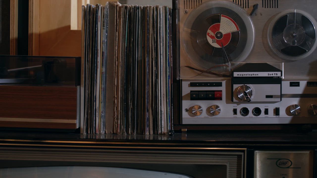 The camera pans on a vintage vinyl records and a reel-to-reel tape ...