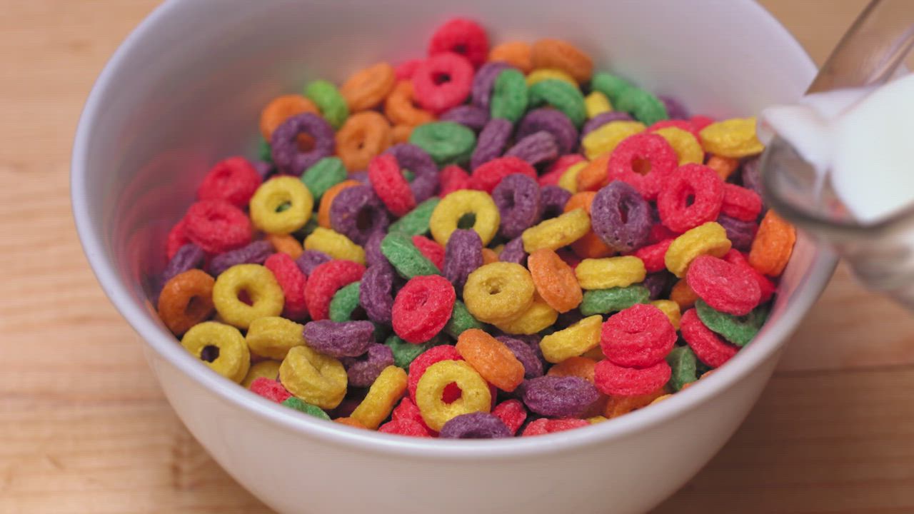 Milk cascade and splashes over a white bowl brimming with colorful ...