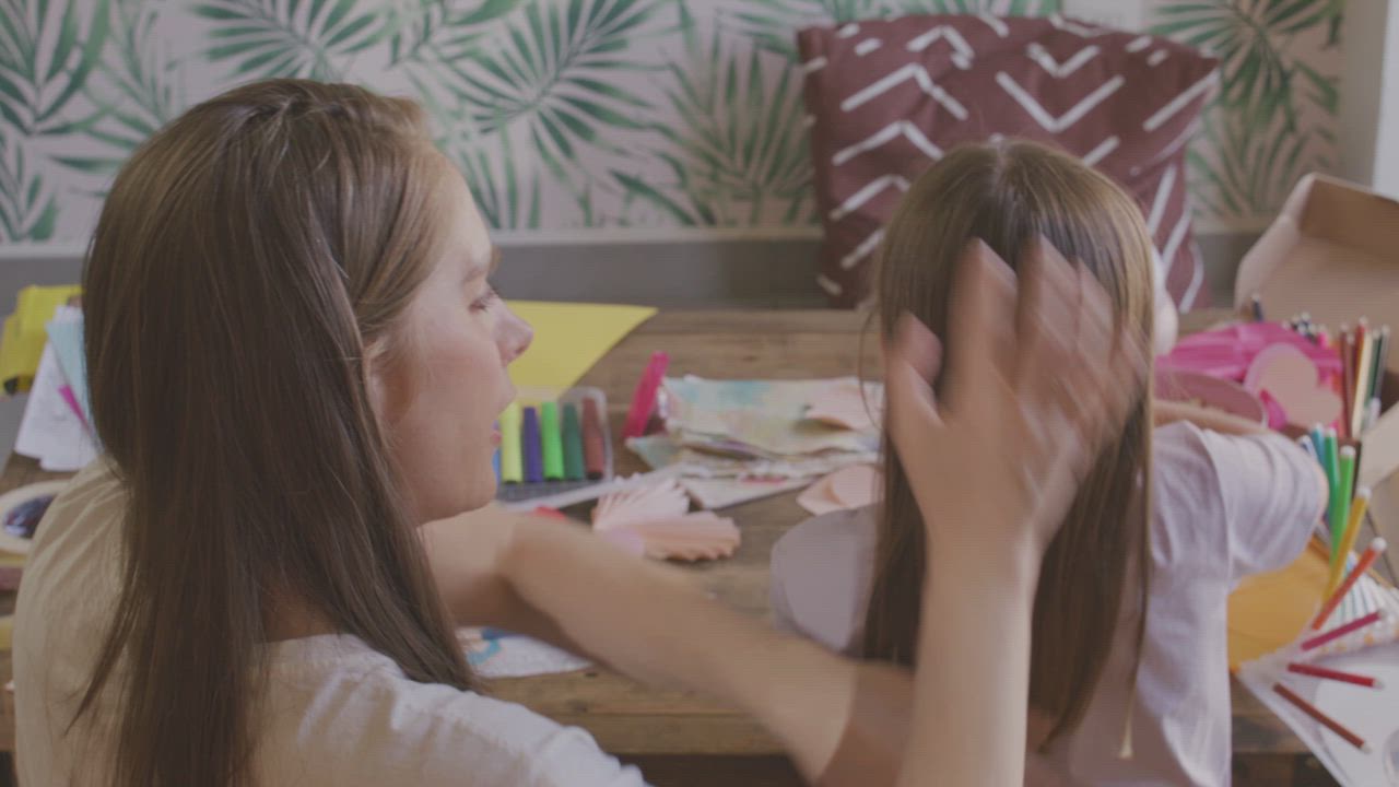 A young mother caresses her little daughters hair while coloring on the ...