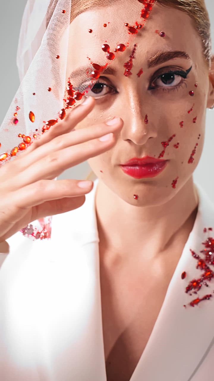 A young woman with red makeup simulating blood that reaches her white ...