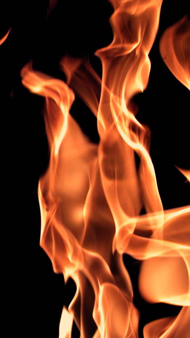 Vertical shot of mesmerizing orange flames flowing upwards against a ...