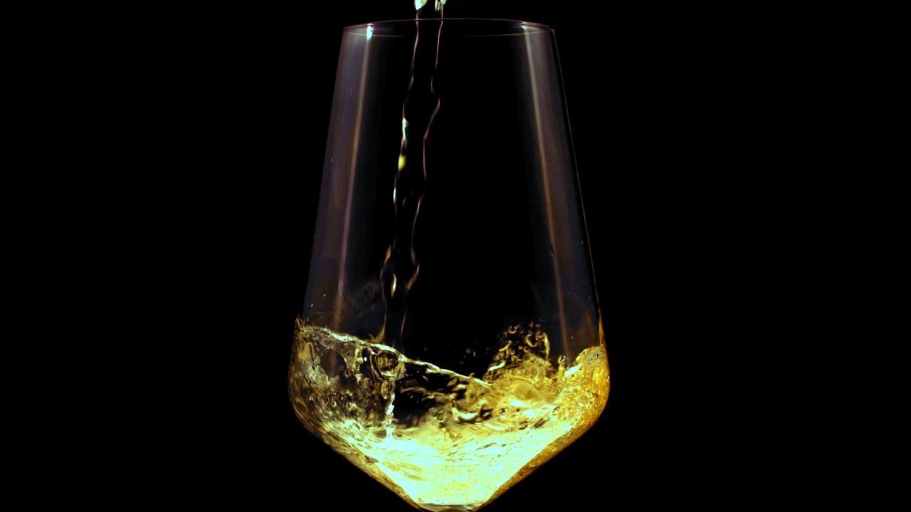 A mesmerizing stream of white wine falling into a elegant wineglass ...