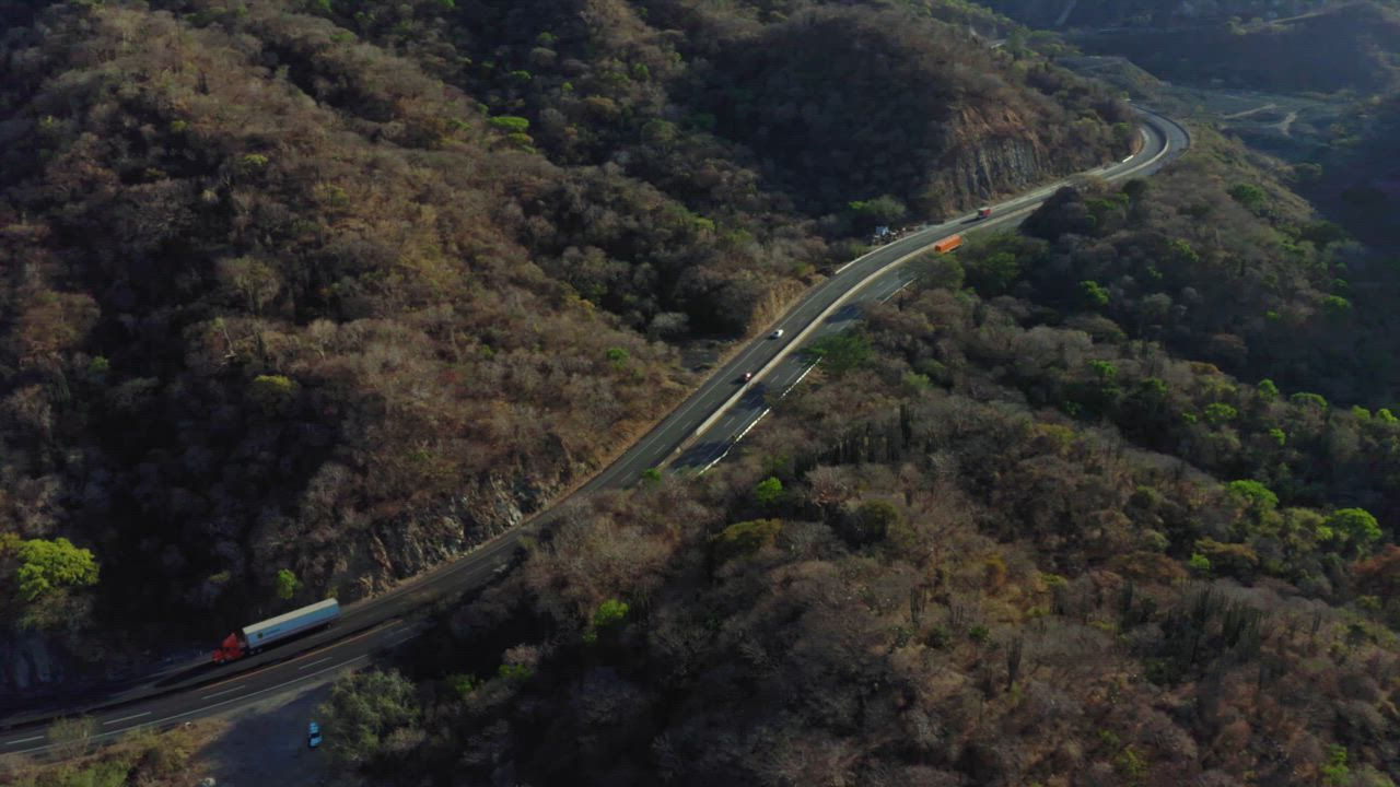 From above, an asphalt highway snakes through an arid landscape dotted ...