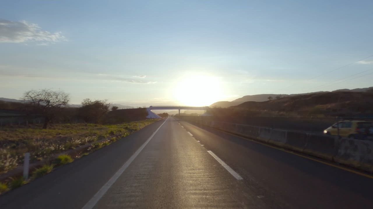 Rear point of view of a vehicle driving on an asphalt road with the sun ...