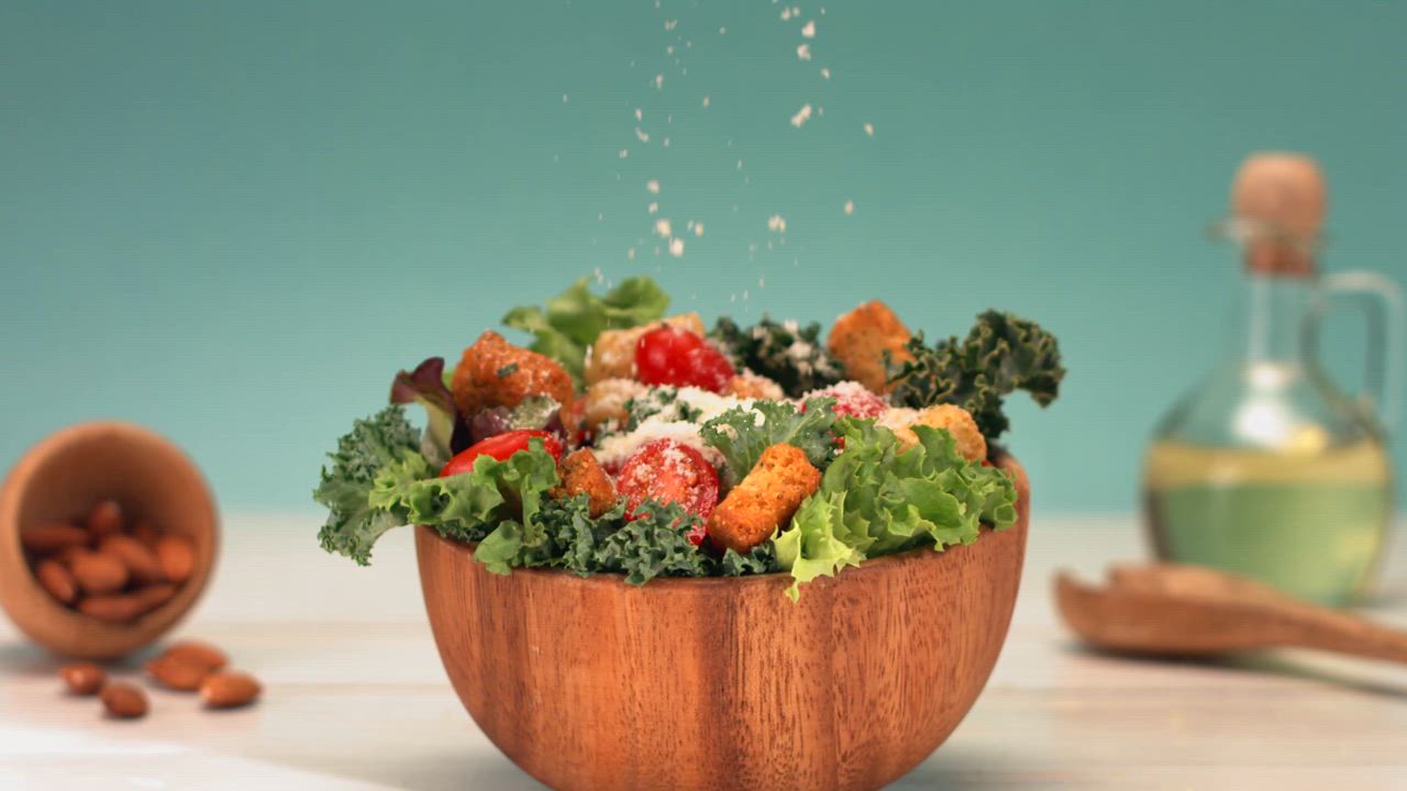 Parmesan cheese cascading into a rustic wooden bowl brimming with a ...