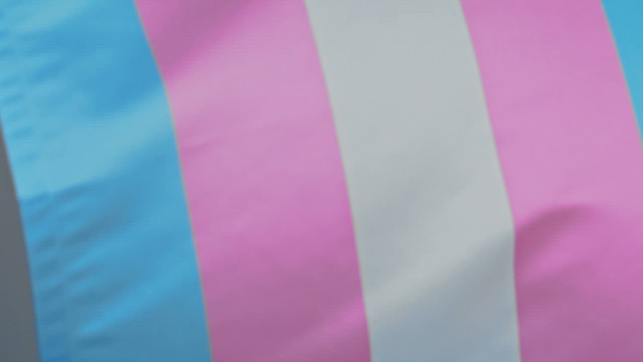A transgender falg waving slowy featuring blue, pink and white colors ...