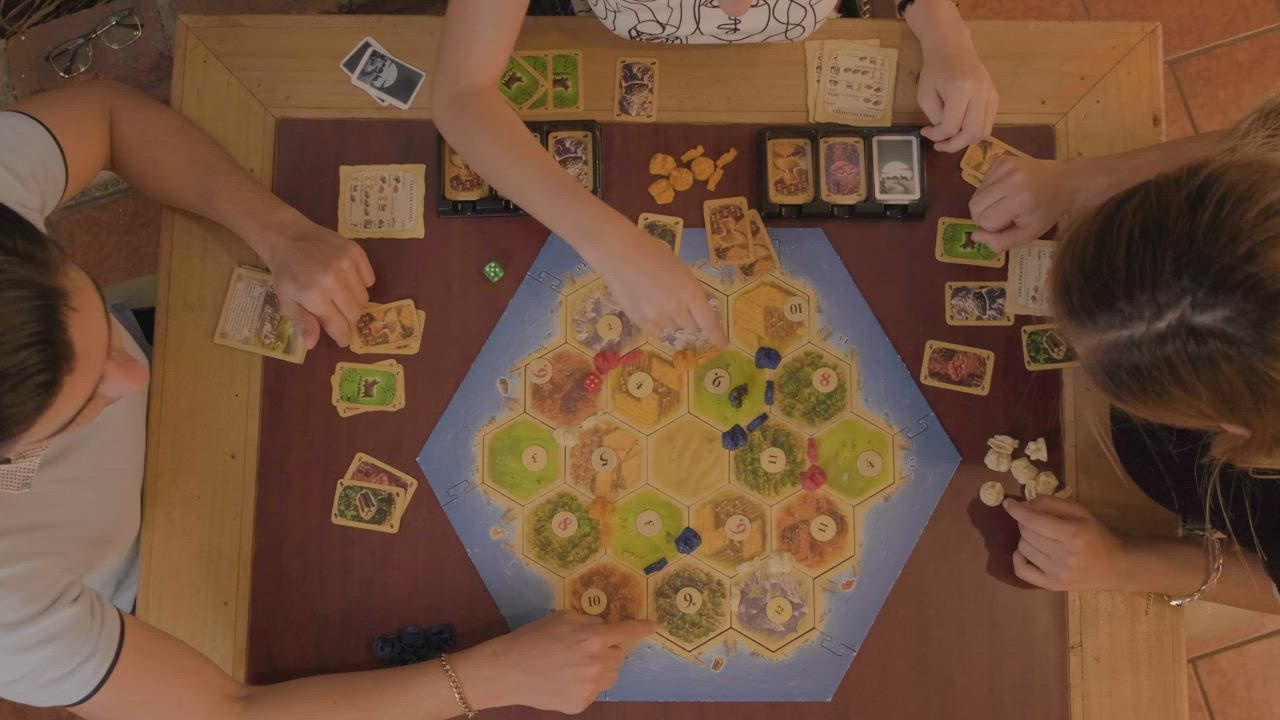 Friends playing Catan sitting at a table - Free Stock Video