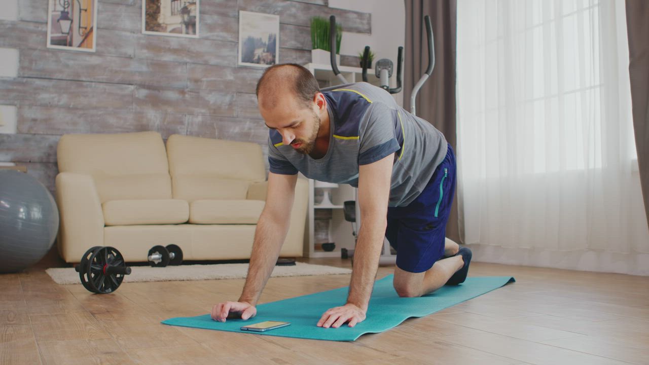 Man sets exercise timer on mobile phone for yoga pose - Free Stock Video