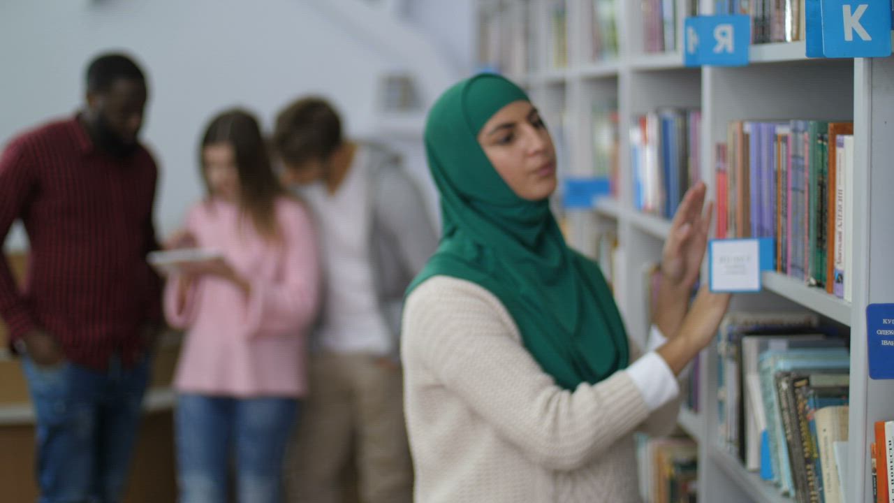 Muslim student browsing a library - Free Stock Video