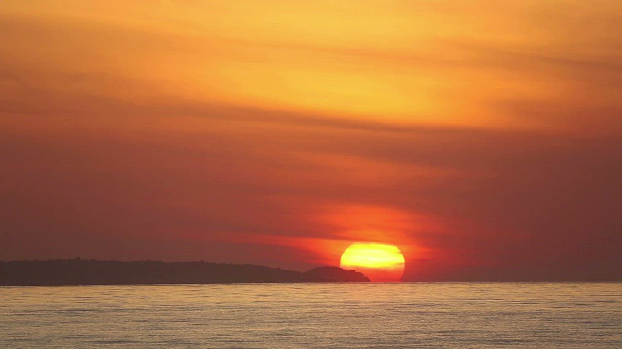 Yellow sun rising at the sea behind the mountains - Free Stock Video