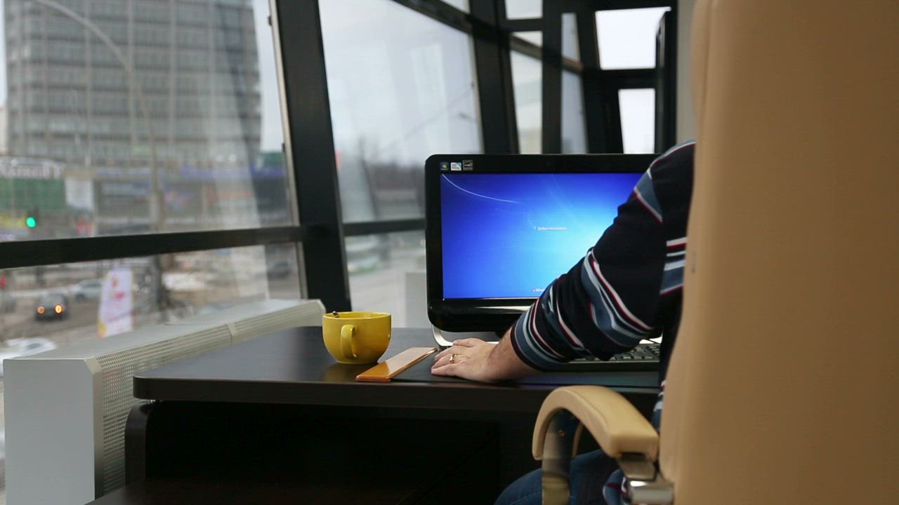 Man working on his computer by the window - Free Stock Video