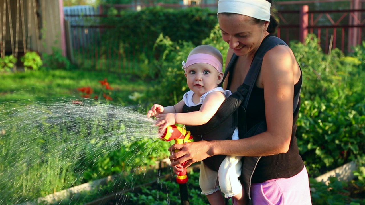 Mom watering the garden with her baby - Free Stock Video
