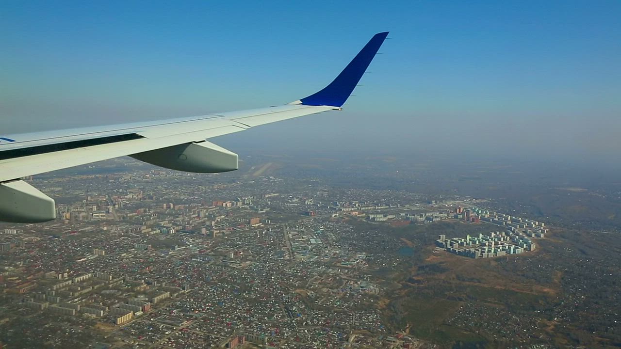 Wing view of an airplane flying above the city - Free Stock Video