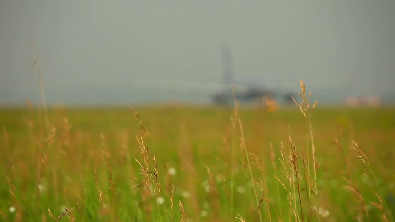 Field and airplane in the background - Free Stock Video