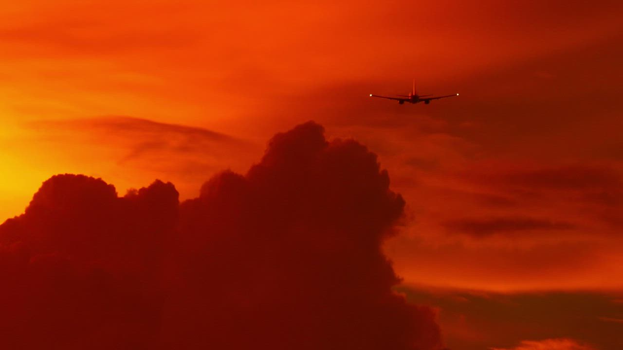 Airplane flying in a red cloudy sky - Free Stock Video