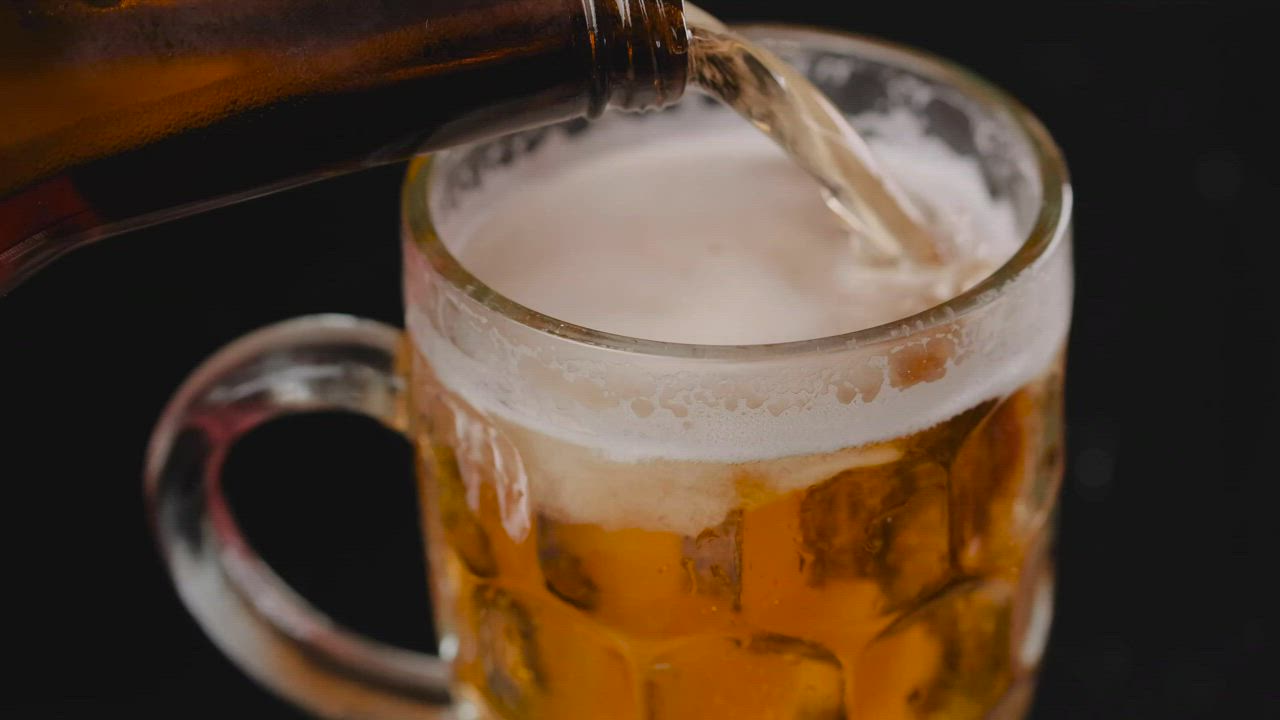 Filling a mug with beer on a dark background - Free Stock Video