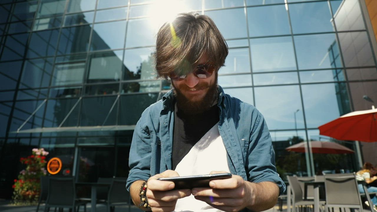 Winner celebrates victory in mobile game on city street - Free Stock Video