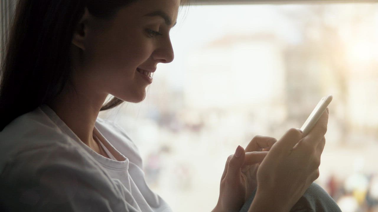 Woman smiles while using mobile app - Free Stock Video