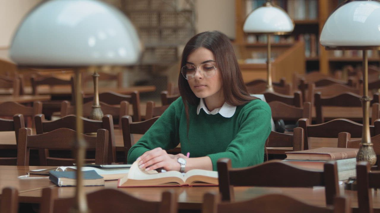 Woman focused on research in library with books - Free Stock Video