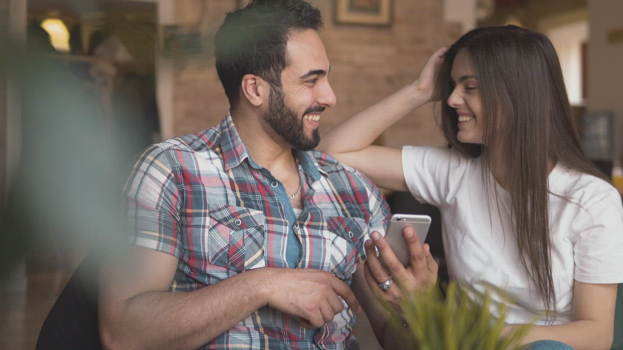 Laughing couple scroll through social media on mobile - Free Stock Video