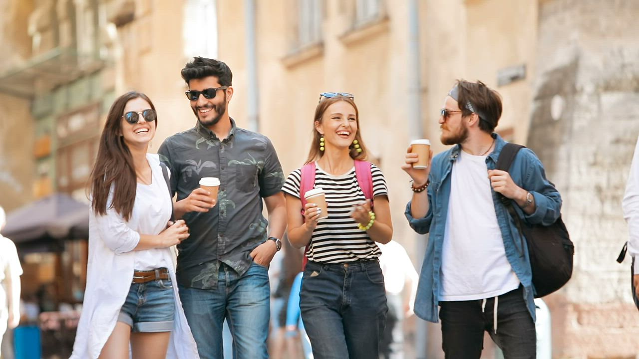 Group of friends walk on street with coffee - Free Stock Video