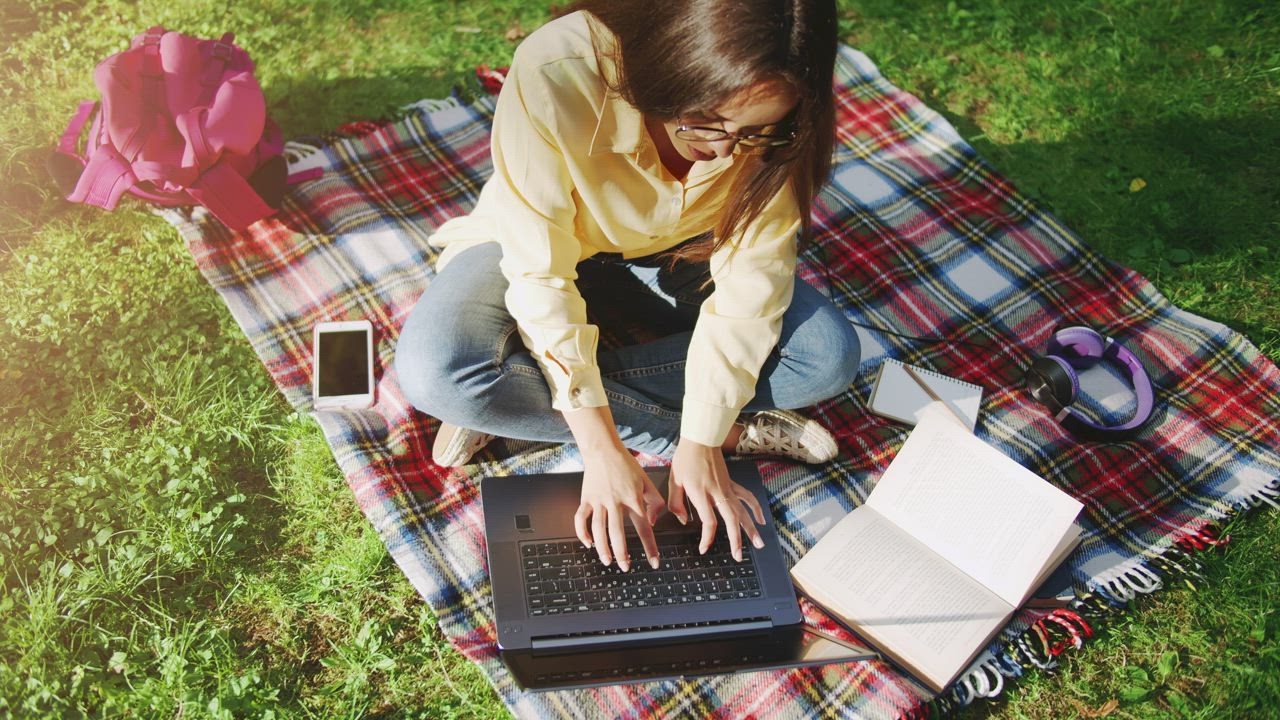 University student learning on laptop in park top view - Free Stock Video
