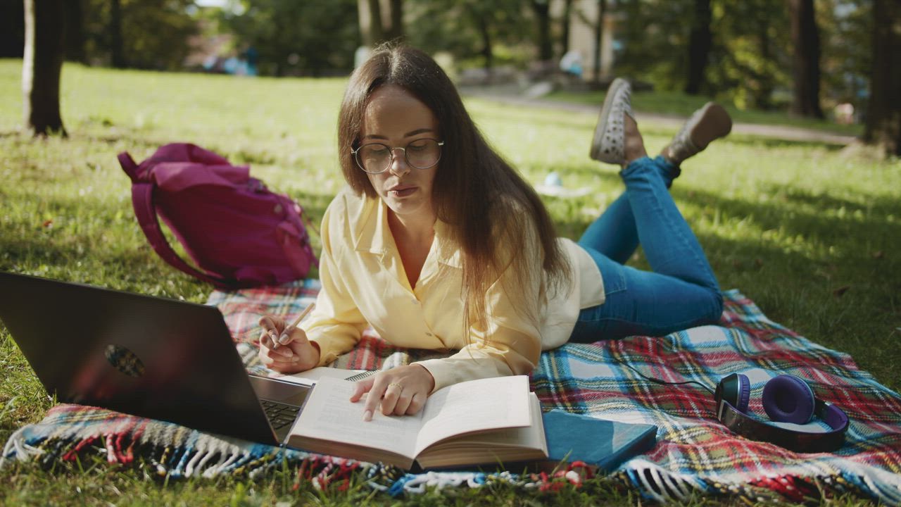 Student learning in park with laptop and book - Free Stock Video