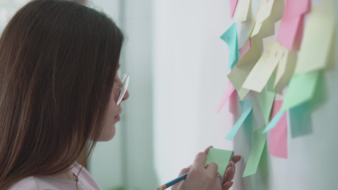 Creative woman writing ideas on sticky notes for marketing project ...