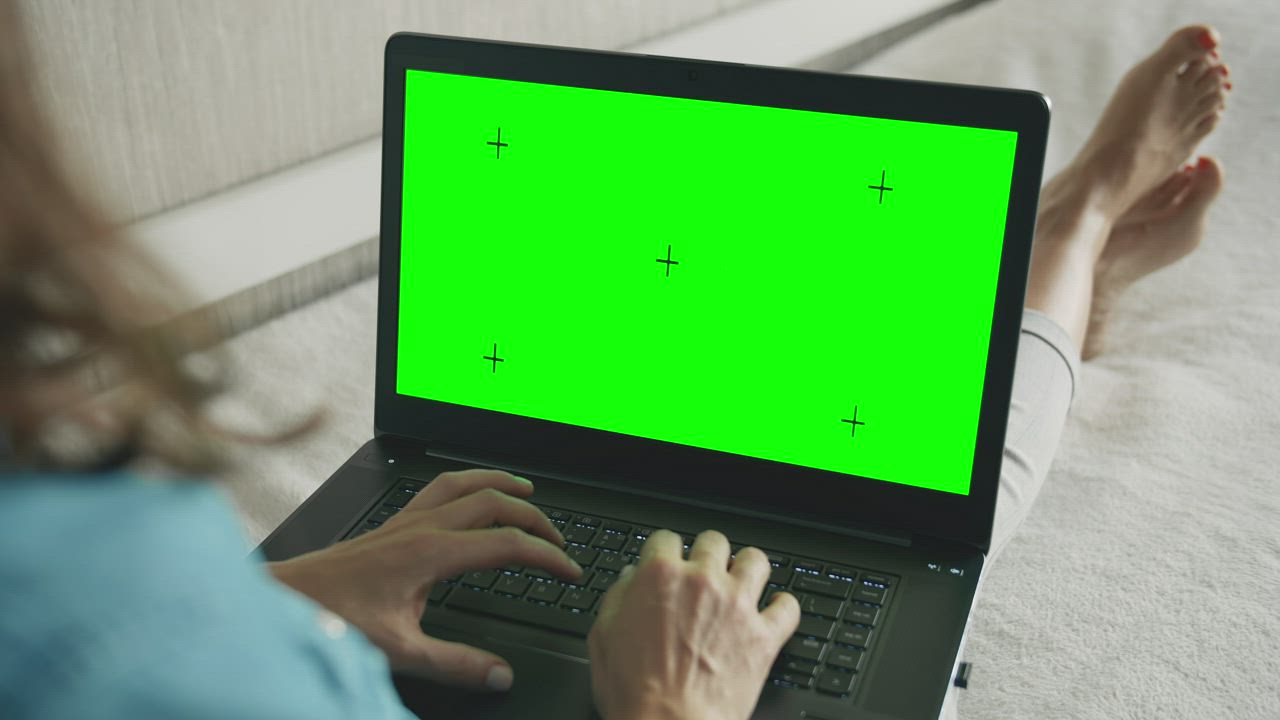 Woman types on greenscreen laptop on sofa - Free Stock Video