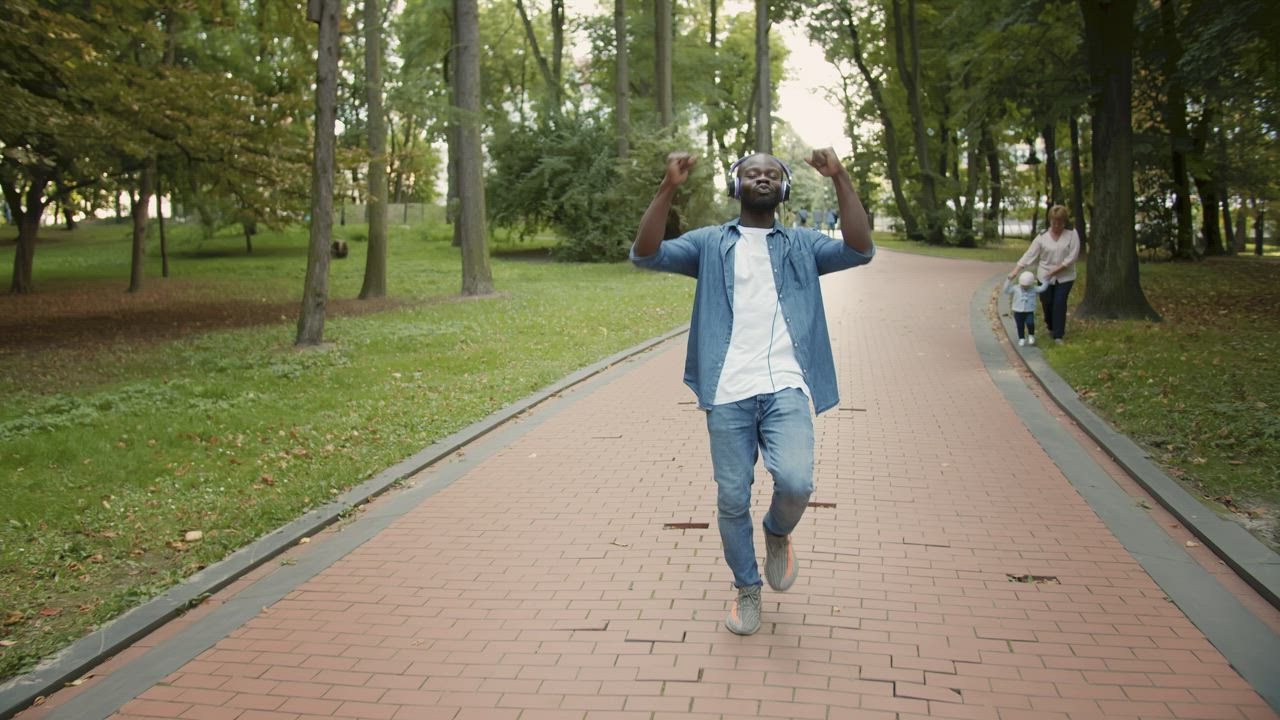 Man dances to hiphop while walking in park - Free Stock Video