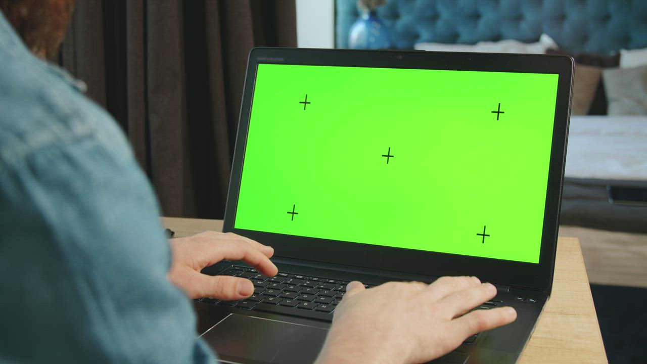Man types on greenscreen laptop in bedroom - Free Stock Video