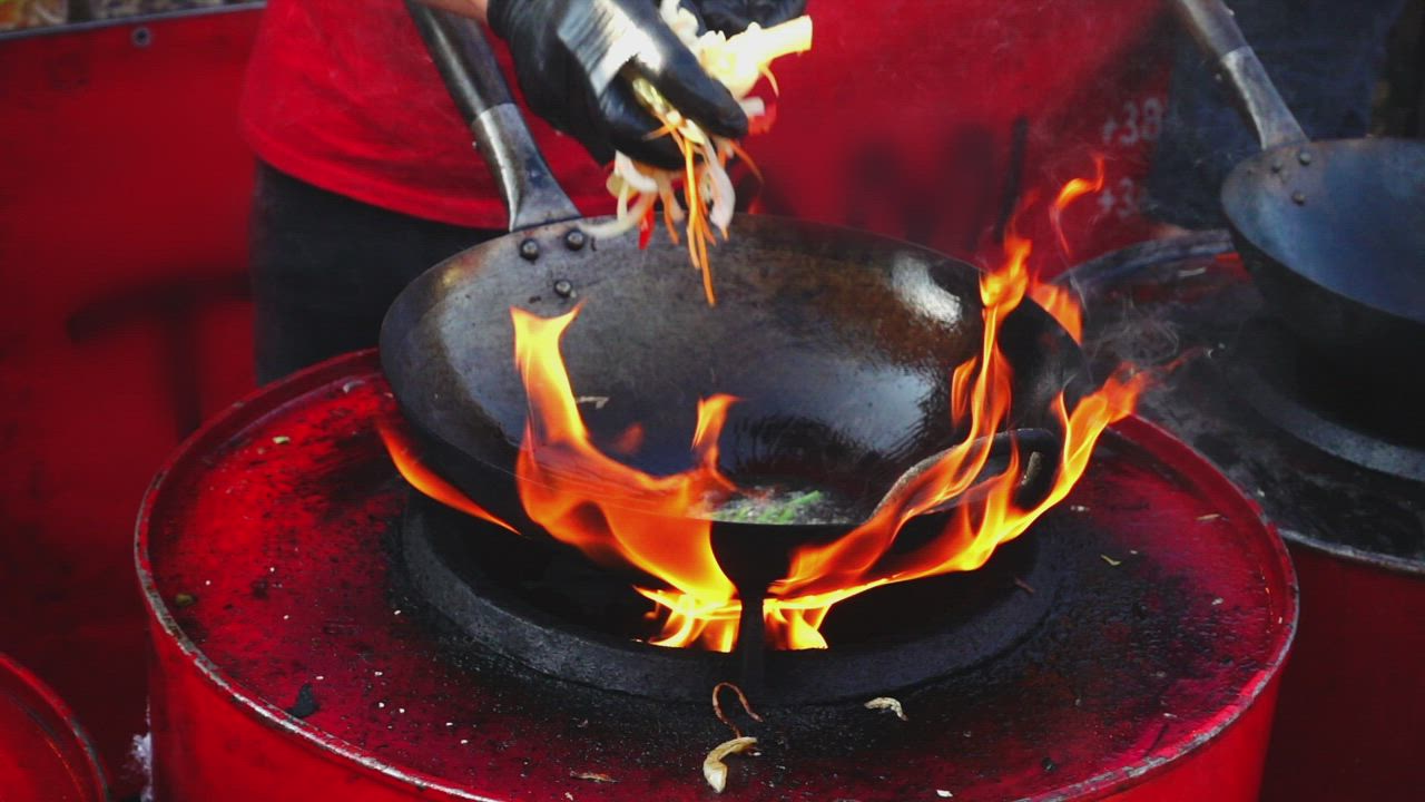 Person cooking in a wok pan with high flame - Free Stock Video