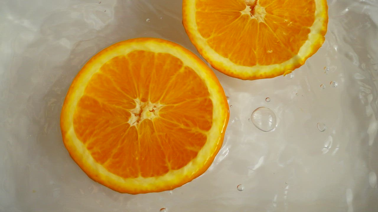 Orange half spinning while floating in water - Free Stock Video